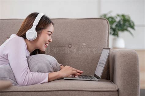 Happy Young Woman Using Laptop At Home Sitting On Soft Couch Lady Is