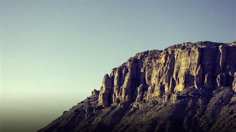 Sunlit Cliff Face Against A Clear Sky Hd Wallpaper Rare Gallery
