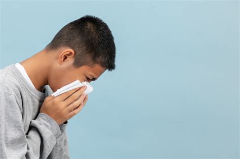Un Niño Estornuda En El Tejido Y Se Siente Enfermo En La Pared Azul