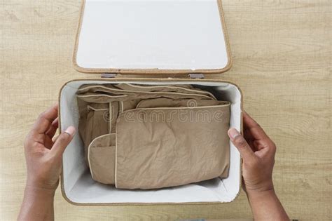 someone is meticulously organizing garments in a storage container on a
