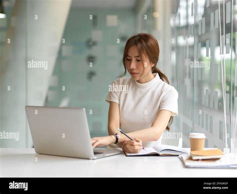 Portrait Of Female Student Doing Assignment With Laptop And Paperwork