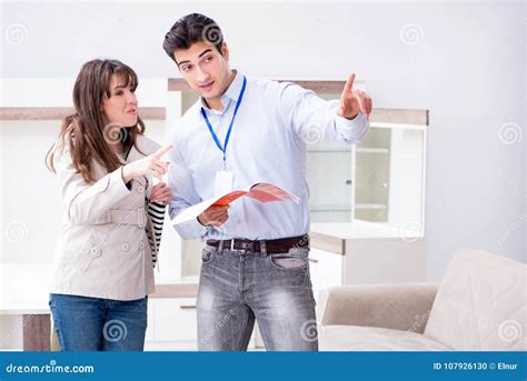 The Salesman Explaining To Woman Customer At Furniture Store Stock