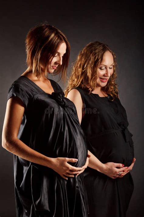 Two Pregnant Women In Black Dresses Touching Their Belly And Thinking