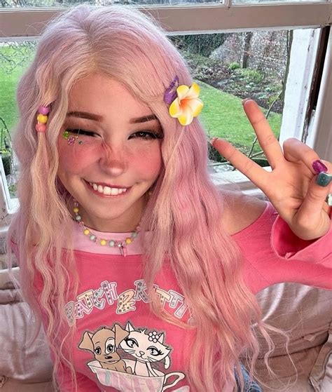 Belle Delphine With Pink Hair And Flowers Making Peace Sign On Bed