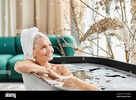 Cheerful Middle Aged Woman With White Towel On Head Taking Bath In Modern Apartment Beauty
