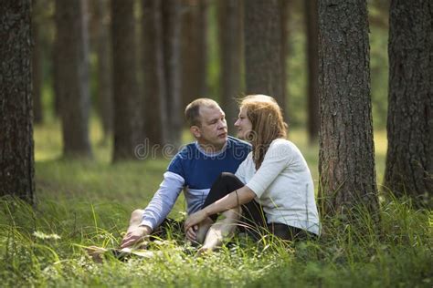 Junge Paare Die Im Gras Nahe Dem Baum Im Park Sitzen Stockbild Bild