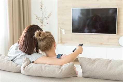 Premium Photo Mother And Daughter Sitting On Sofa Watching Tv