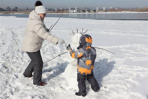 A Mulher E O Rapaz Pequeno Que Constroem Um Boneco De Neve Imagem De