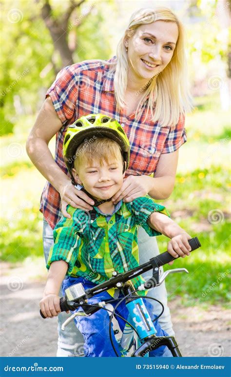 La Giovane Madre Veste Il Suo Casco Della Bicicletta Del Figlio