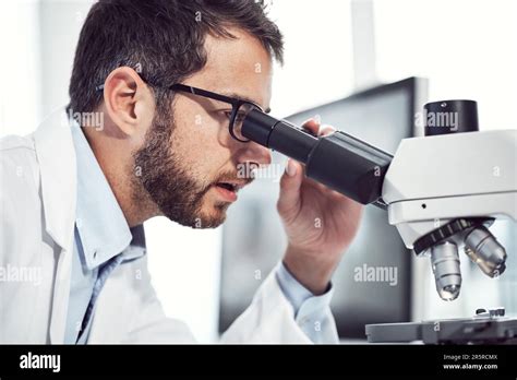 Seeing Is Believing A Focused Young Male Scientist Looking Through A Microscope Inside Of A