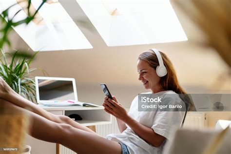 Young Woman Wearing White Clothes And White Headphones Sits With Her