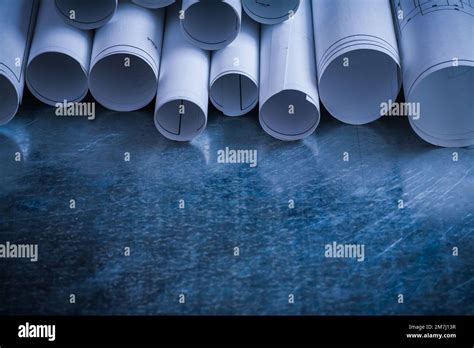 Rolls Of White Blueprints On Scratched Metallic Background Building And Architecture Concept
