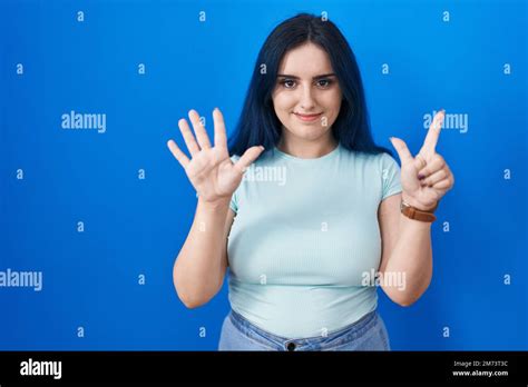 Young Modern Girl With Blue Hair Standing Over Blue Background Showing