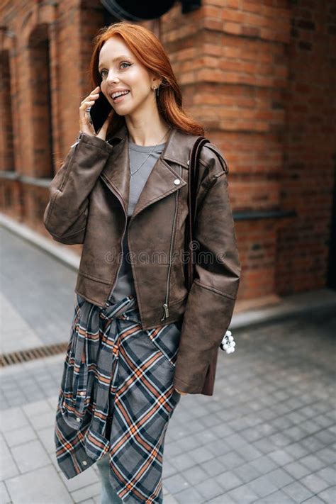 Vertical Shot Of Cute Redhead Woman Happily Chatting On Phone Standing