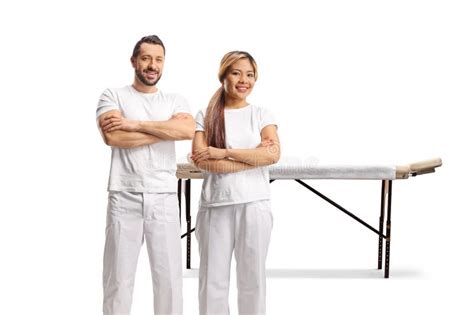 Male And Female Massage Therapists In Front Of A Massage Table Stock