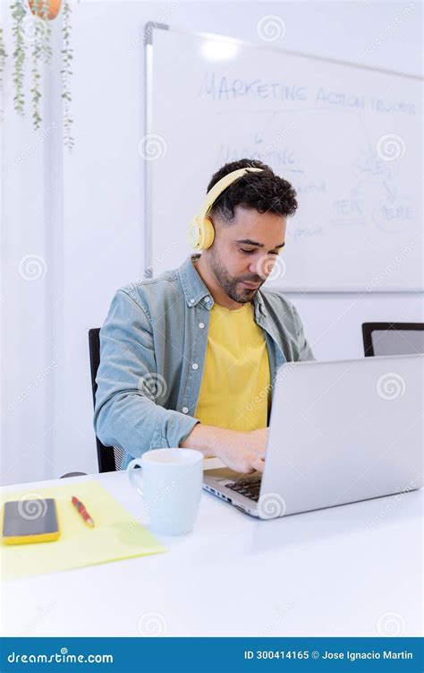 Man Using Headphones While Working With A Laptop In The Office Stock