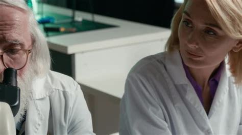 Female Colleague Assisting Senior Male Scientist In Laboratory During