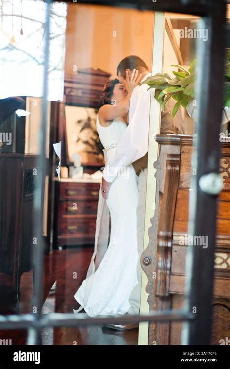 Bride And Groom Share A Romantic Kiss Captured Through A Window Stock