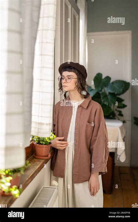 Pensive Introvert Young Woman Spy From Behind Curtain Into Window On