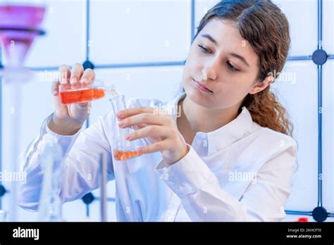 Young Woman In A Microbiology Laboratory Fills A Cell Culture Flask