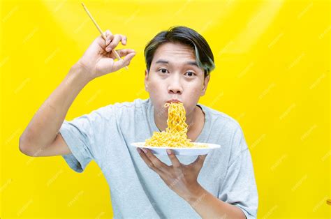 Premium Photo A Man Eating Noodles On A Yellow Background Asian Man