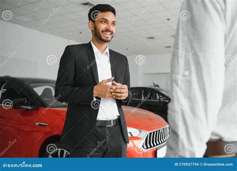 Good Looking Cheerful And Friendly Indian Salesman Poses In A Car