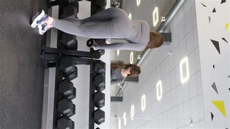 Beautiful Slender Girl With Long Hair Lifts Dumbbells In The Gym