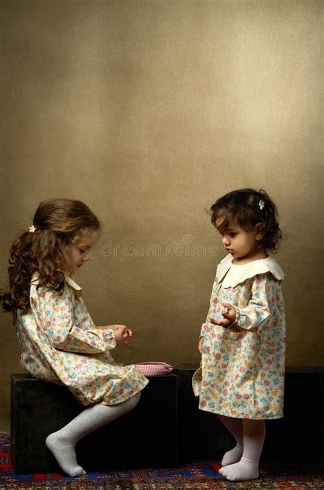 Two Sisters Sitting On Blocks Cute Sisters In Matching Floral Dresses