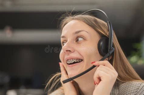 A Woman With Braces On Her Teeth Talks On A Headset Helpdesk Stock