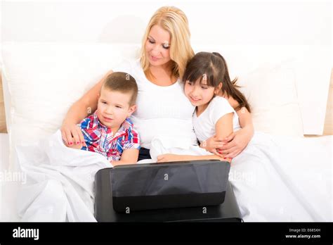 A Mother Using With Her Son And Babe A Laptop Computer In Bed Stock Photo Alamy