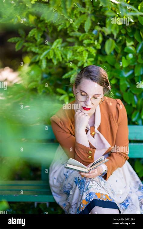 Young Intellectual Woman Dressed In 1940s Clothing In A Garden Stock