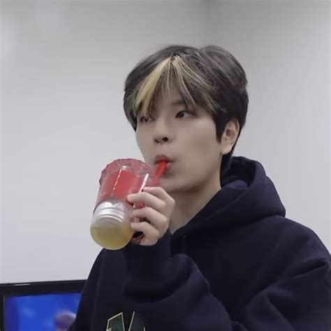 A Young Man Drinking From A Plastic Cup While Wearing A Hoodie And