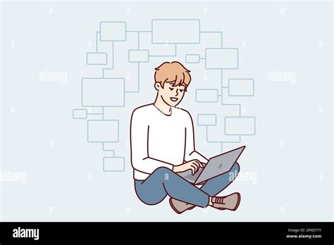 Young Man Programmer Sits Cross Legged On Floor With Laptop On Lap And Creates Web Application