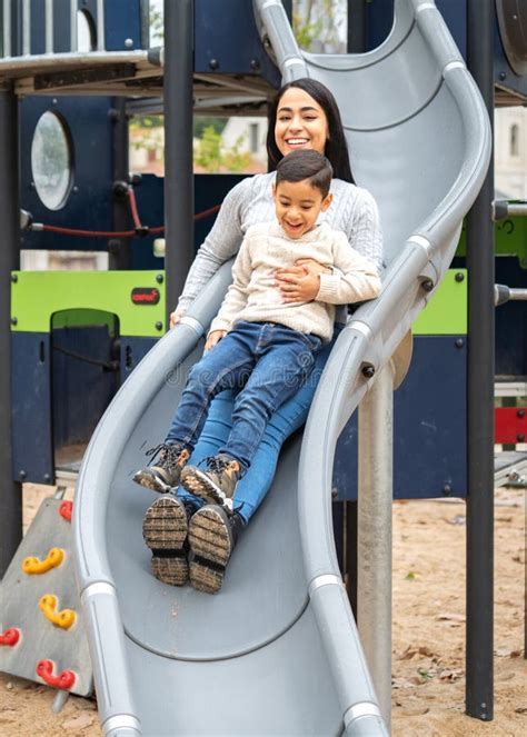 Single Mother And Son Having Fun Together In A Slide In A Playground