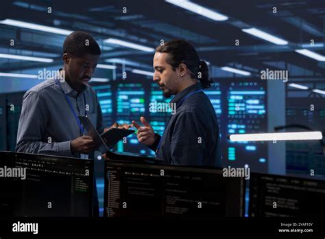 Engineers In Data Center Using Tablet And Laptop To Check For Server