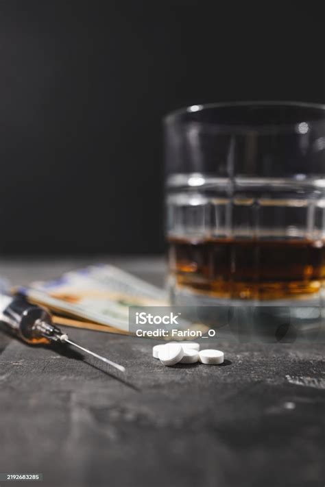 흰색 마약 알약 유리잔에 담긴 알코올 음료 헤로인이 든 주사기 투명 봉지에 든 코카인 가루 어두운 배경에 있는 미국 달러 지폐 중독과 나쁜 습관의 개념 0명에 대한 스톡