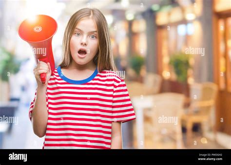 Young Beautiful Girl Yelling Through Megaphone Over Isolated Background
