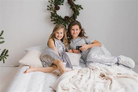 Two Young Sisters Girls Are Sitting On Bed One Of Them Holding