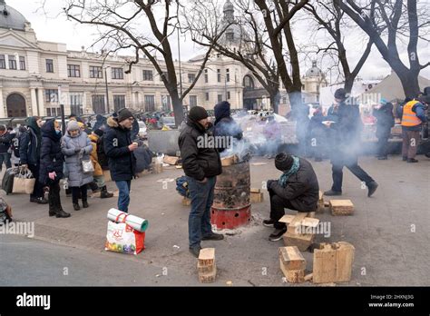 People Warm Up By The Fire Burning In An Iron Barrel Outside The Main