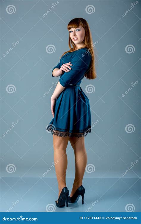 Portrait Of A Plus Size Female Redhead Model Posing In Blue Dress Over