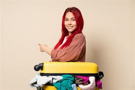Premium Photo Traveler Girl With A Suitcase Full Of Clothes On Beige