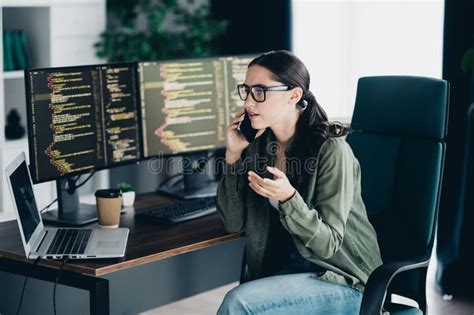 Young Female Programmer Working On Coding Tasks At Her Desk In A Modern Workspace With Multiple