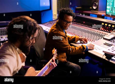 Artist Playing A New Record On His Guitar In Control Room Recording