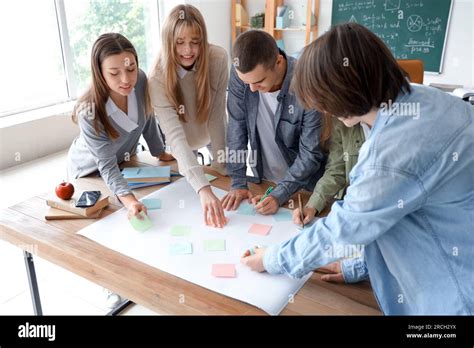Group Of Teenage Students Performing Task At Table In Classroom Stock