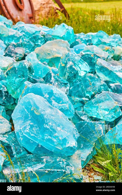 Pile Of Cloudy Blue Glass Crystals Laying In Grassy Field Vertical