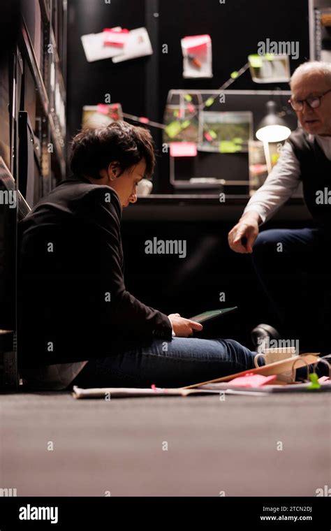 Tired Police Officer Analyzing Victim Report In Arhive Room Discussing Crime Scene Evidence