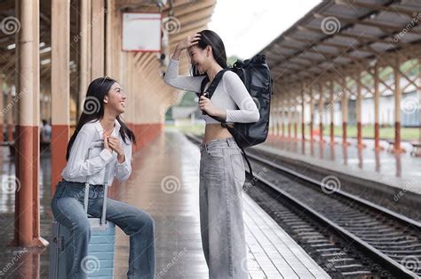 Young Lesbian Couple Waiting For Train At Station Smiling And Enjoying