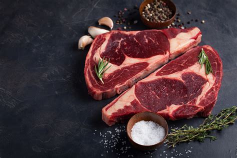 원시 신선한 대리석된 고기 스테이크 Ribeye 블랙 앵거스 검은색 대리석에 어두운 돌 테이블에 향신료와 함께 쇠고기 복사 공간