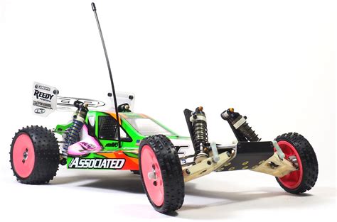 A Remote Controlled Buggy Is Shown On A White Surface With Pink Wheels And Red Rims