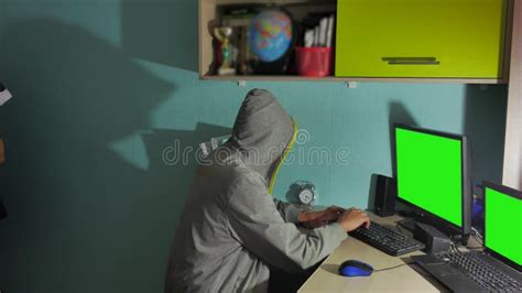 Male Hacker Working On A Computer Man Hacker In Hood Hiding Indoor His